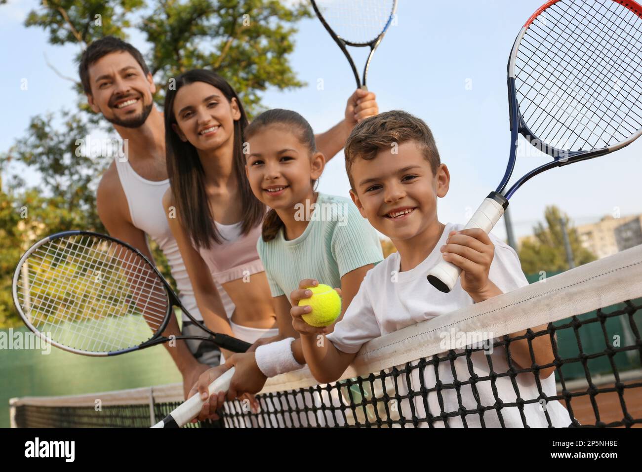 Happy family with tennis rackets on court outdoors Stock Photo - Alamy