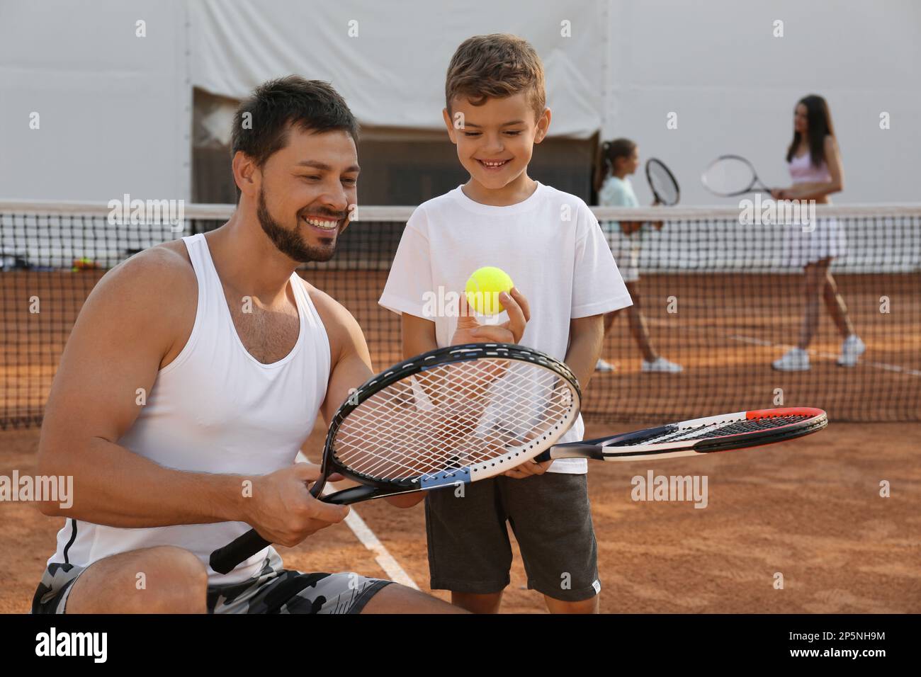 Father teaching son to play tennis on court Stock Photo - Alamy