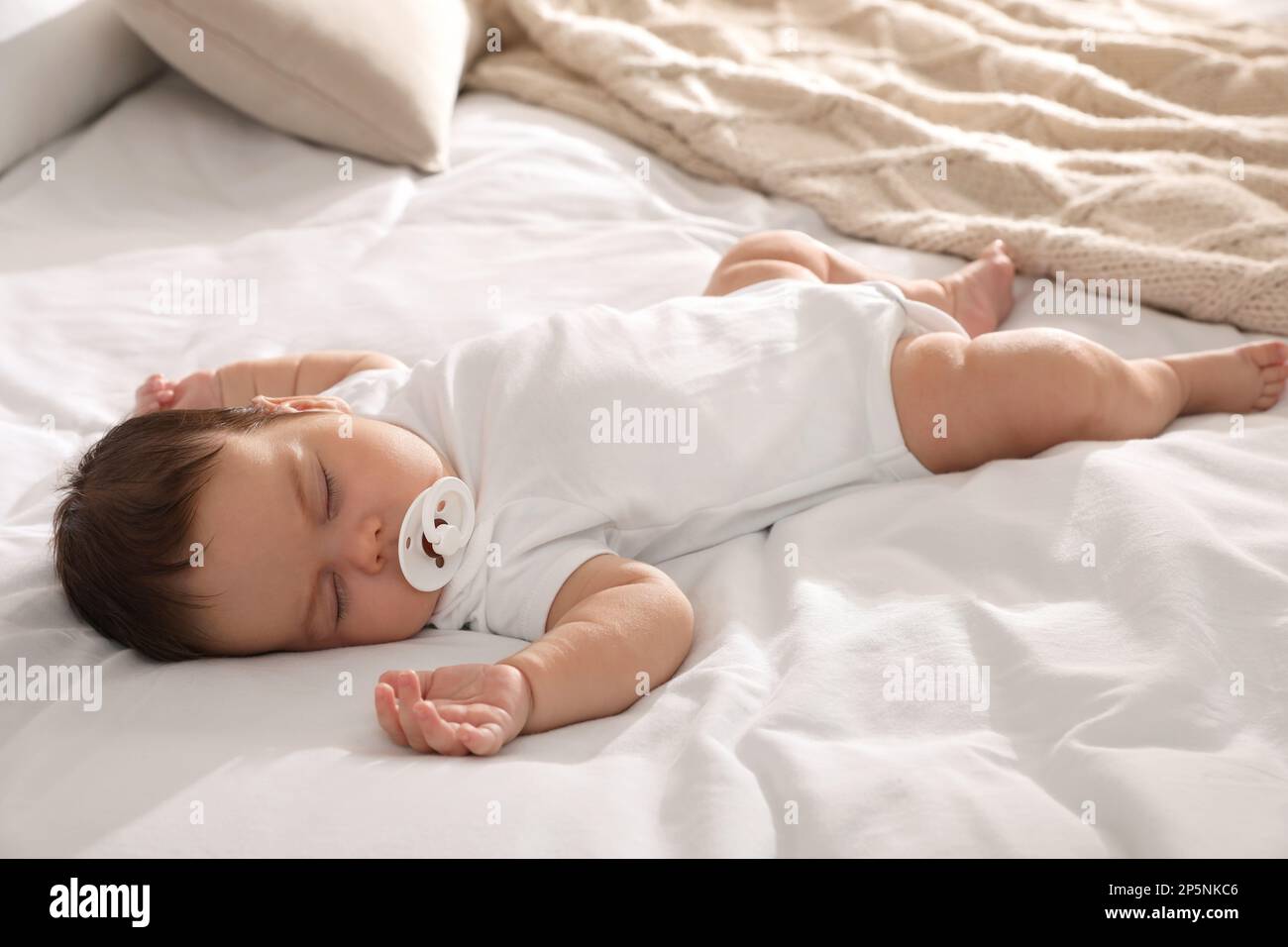 Cute little baby with pacifier sleeping on bed Stock Photo - Alamy