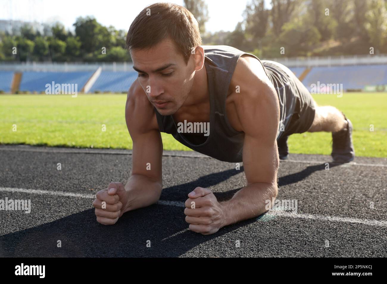 Sporty man doing plank exercise at stadium Stock Photo - Alamy