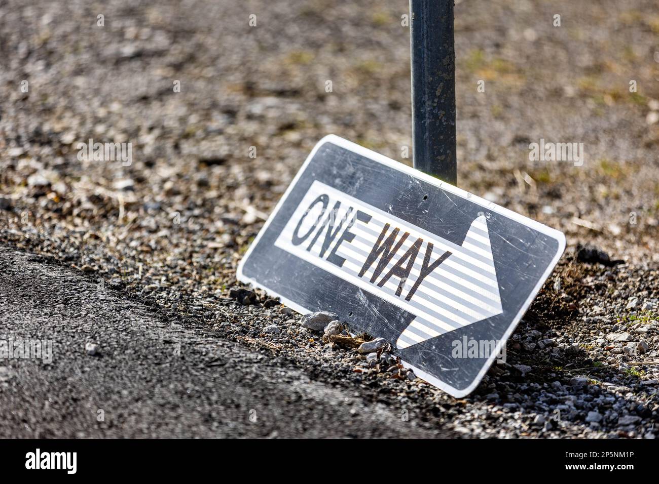 A one-way street sign lying on the side of a roadway, indicating a need ...