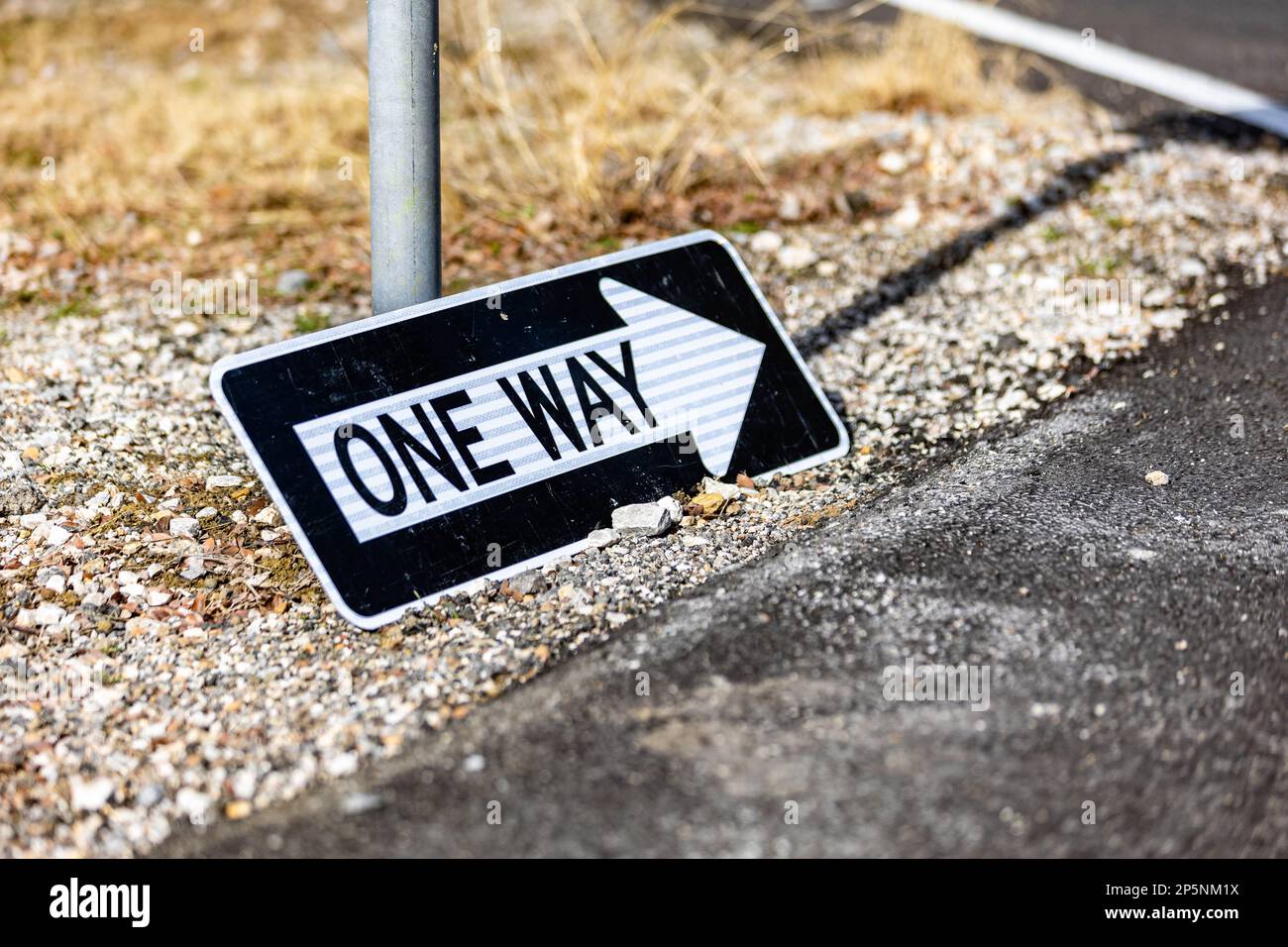 A one-way street sign lying on the side of a roadway, indicating a need ...