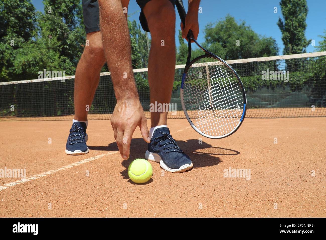 Man picking up tennis ball on court, closeup Stock Photo - Alamy