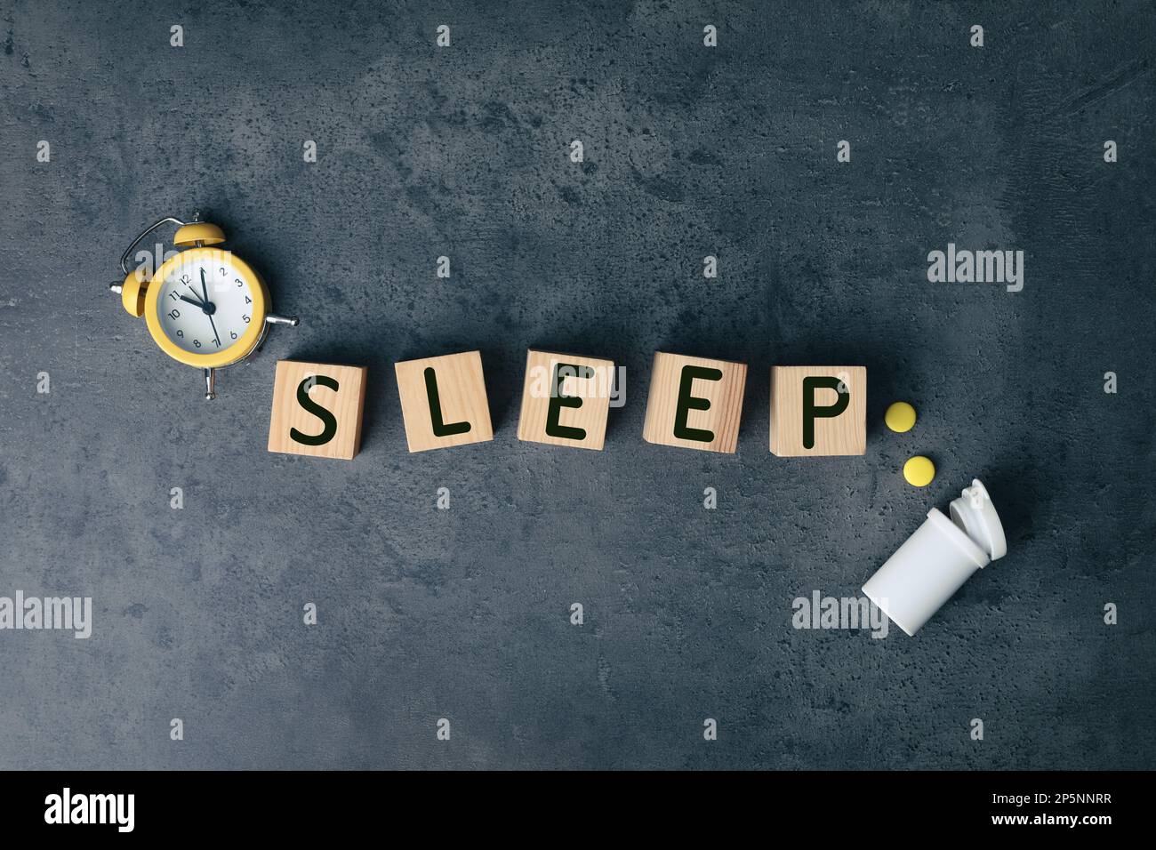 Word Sleep made of wooden cubes near pills and alarm clock on grey ...