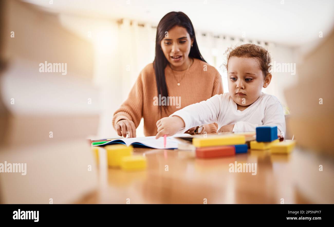 Learning, education and mother with kid drawing in book in home for ...