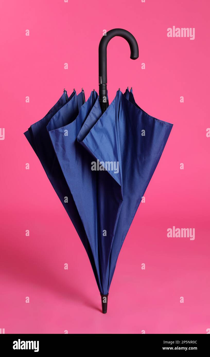 Stylish closed blue umbrella on pink background Stock Photo - Alamy