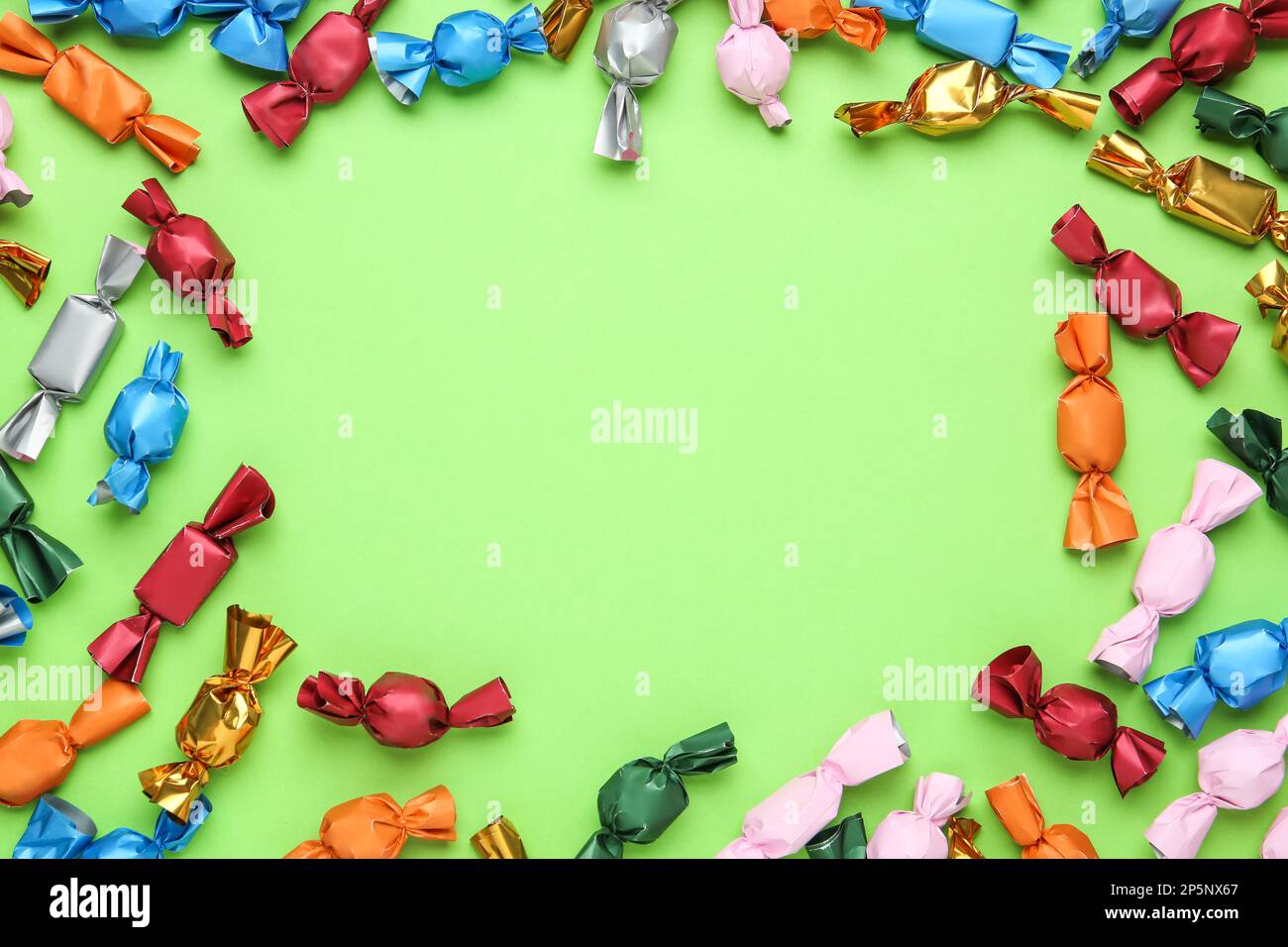 Frame of candies in colorful wrappers on light green background, flat ...