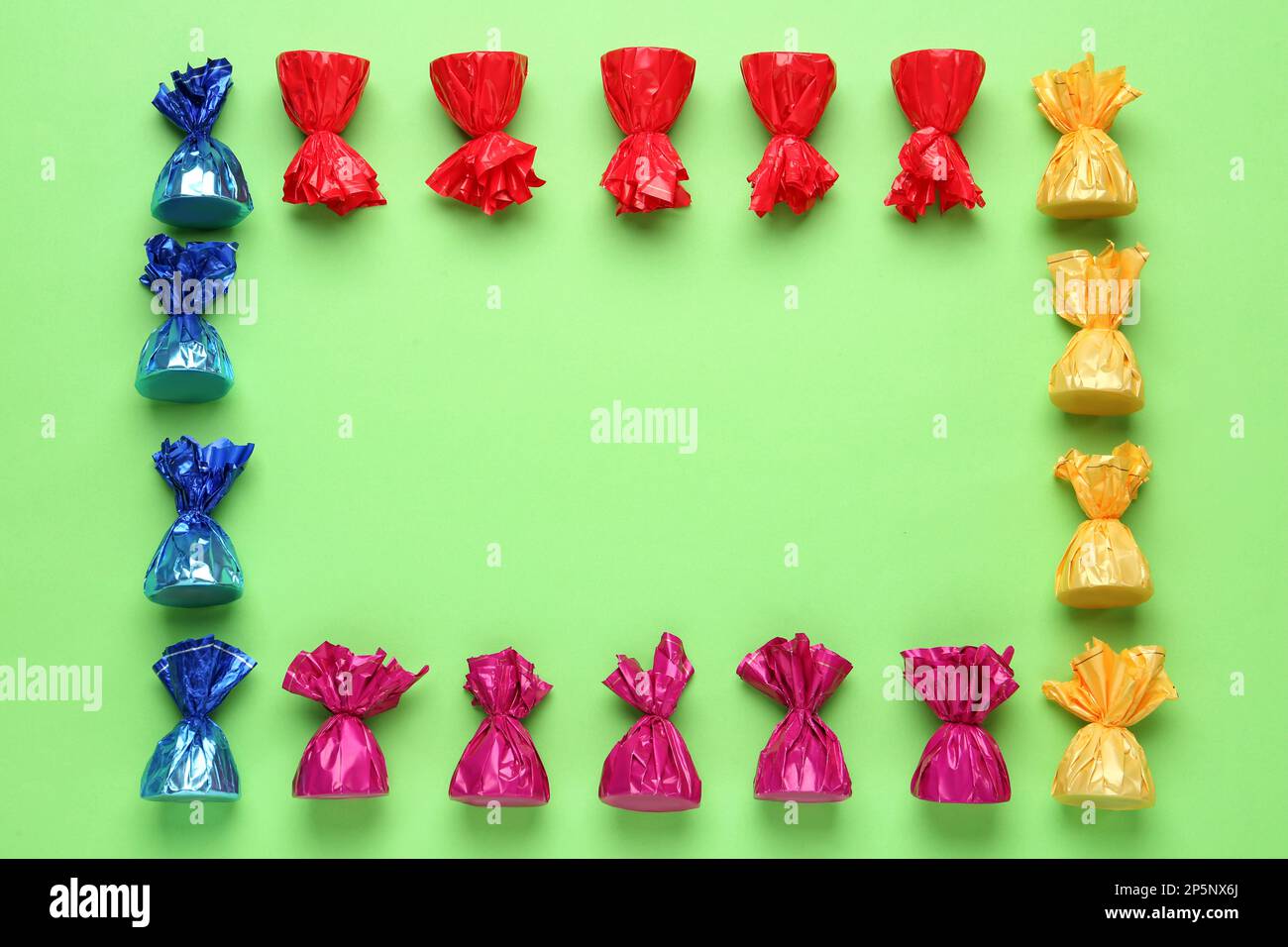 Frame of candies in colorful wrappers on light green background, flat ...