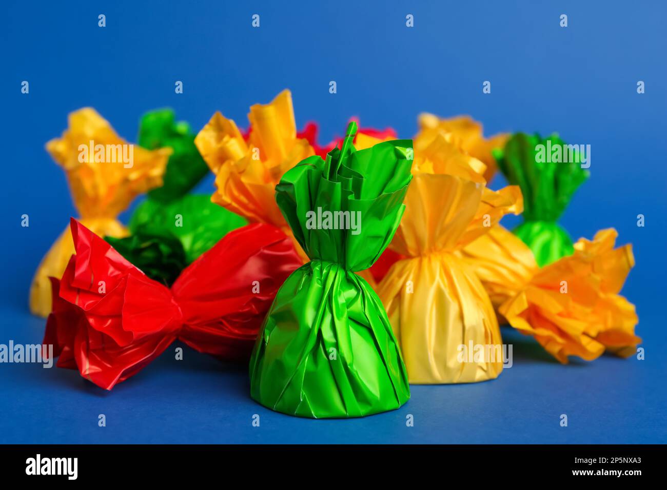 Candies in colorful wrappers on blue background Stock Photo - Alamy