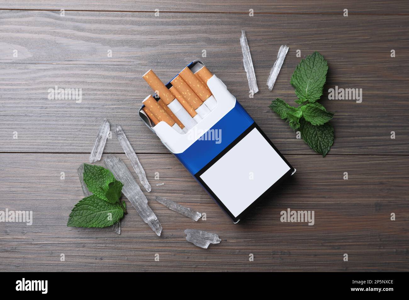 Pack of cigarettes, menthol crystals and mint on wooden table, flat lay ...