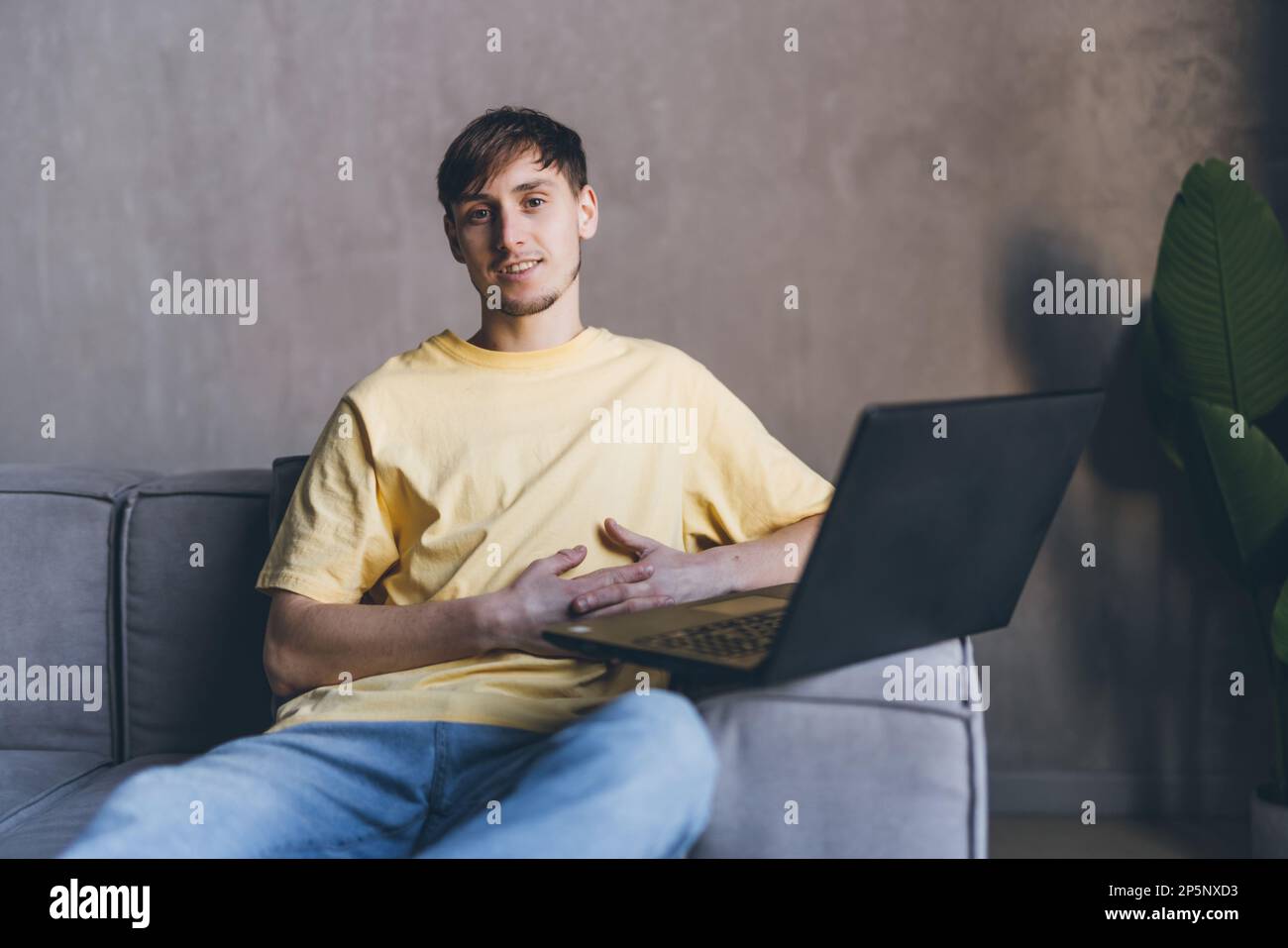 Man sitting on couch with laptop Stock Photo - Alamy