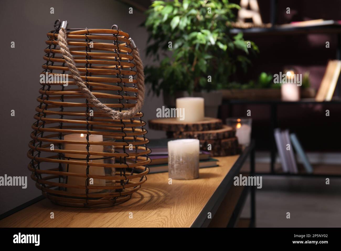 Burning scented candles on wooden console table in room. Space for text ...