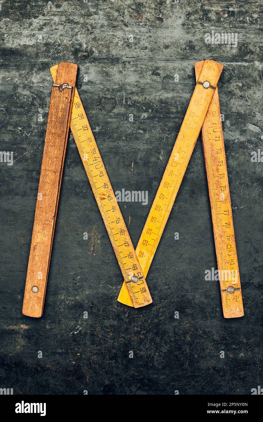 M like measuring. Wooden measure. Old ruler on metal surface. Measuring ...