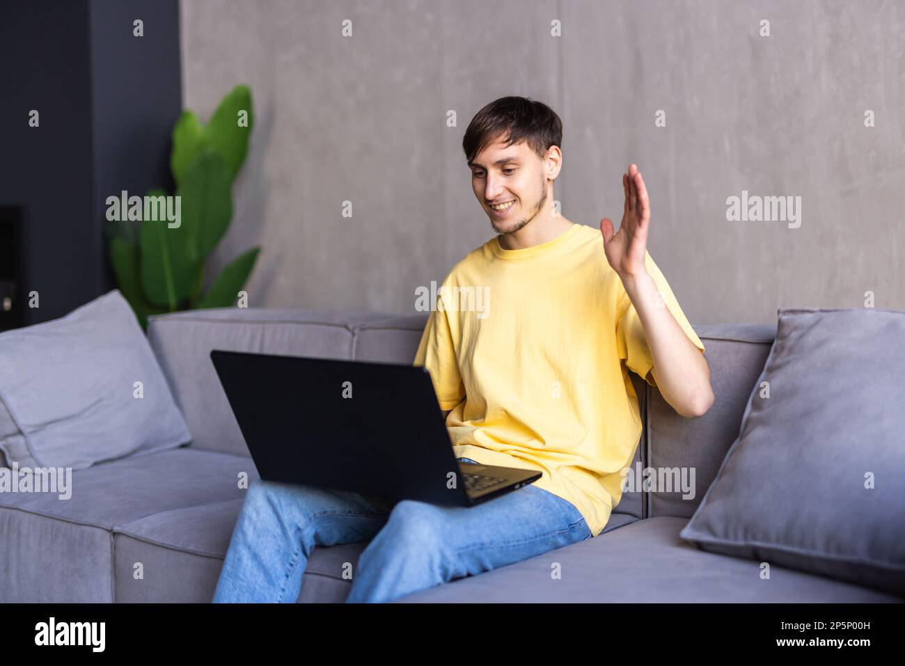 Portrait of happy millennial man making video call on laptop sitting on ...