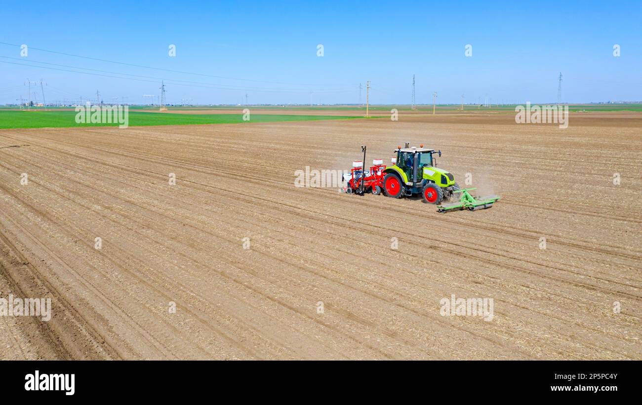 Above view, of tractor as pulling mechanical seeder machine over arable ...
