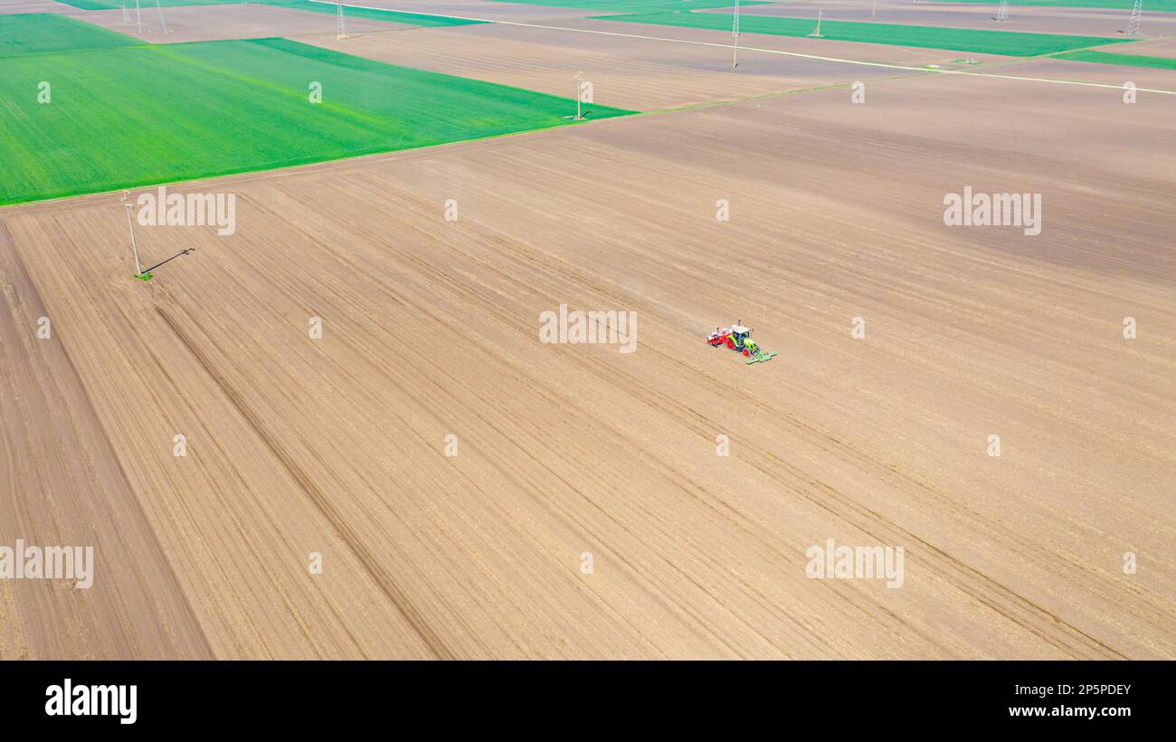 Above view, of tractor as pulling mechanical seeder machine over arable ...