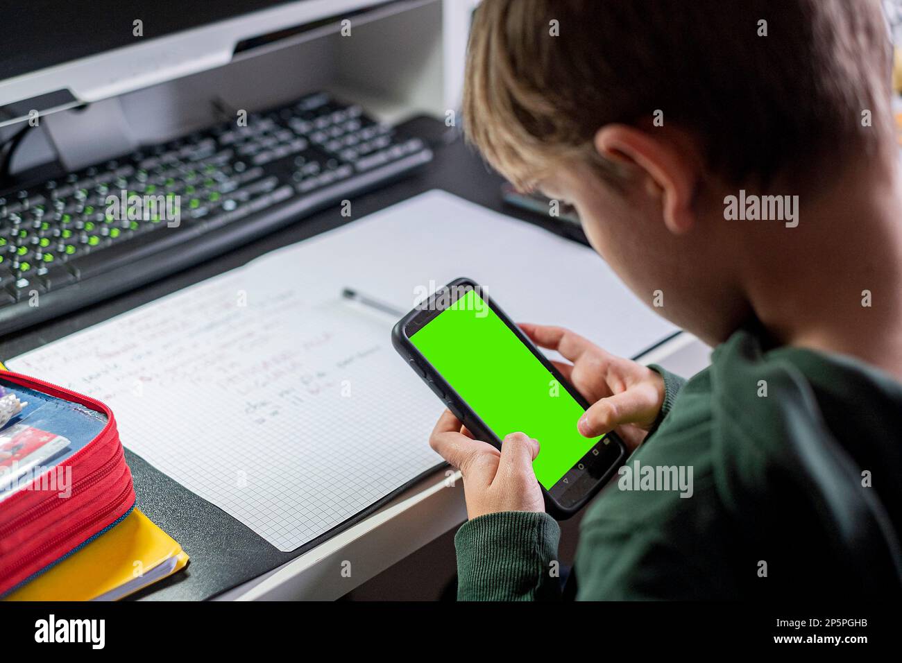 Boy studying at home with smartphone and doing school homework ...