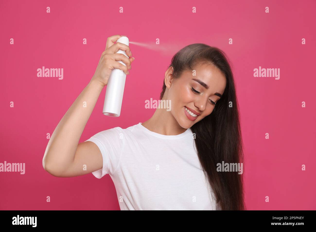 Young woman applying dry shampoo against pink background Stock Photo ...