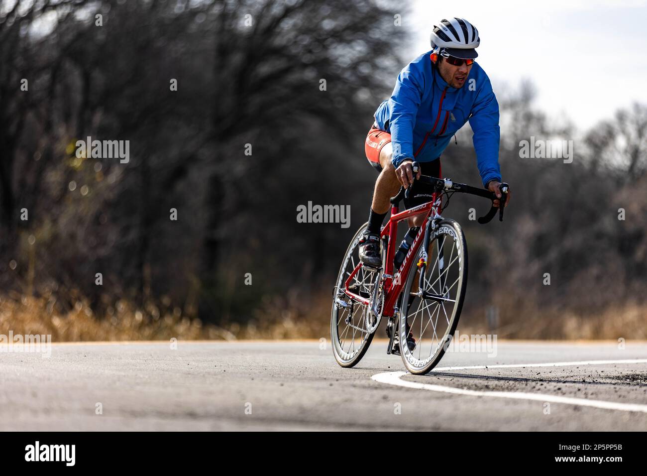 A concentrated male cyclist in a bright blue cycling jersey during the ...