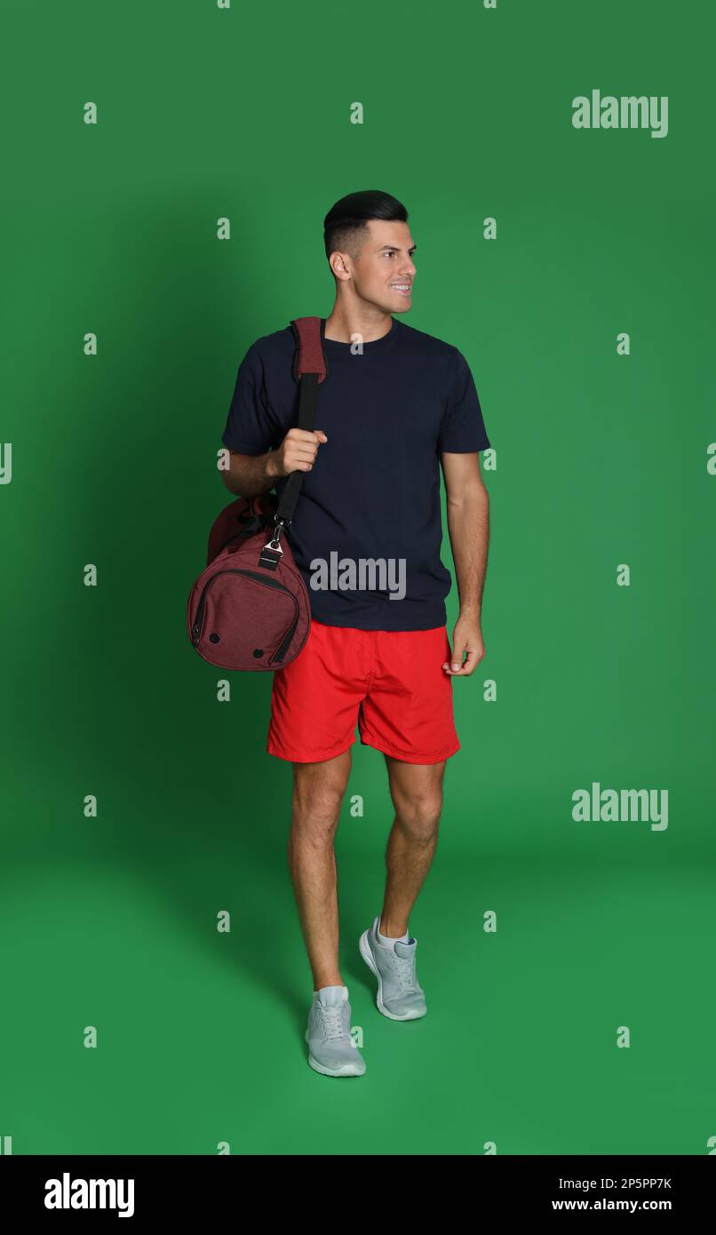 Handsome man with sports bag on green background Stock Photo - Alamy