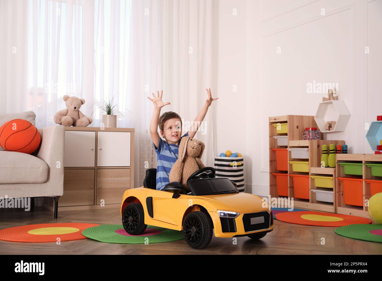 Little child with bunny sitting in toy car indoors Stock Photo - Alamy