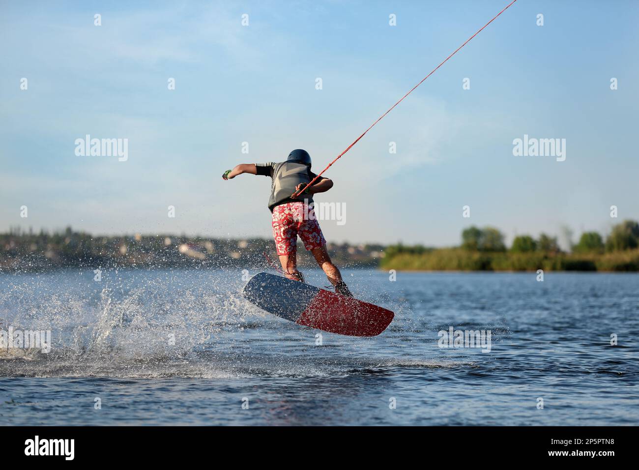 Teenage wakeboard doing trick on river, back view. Extreme water sport ...
