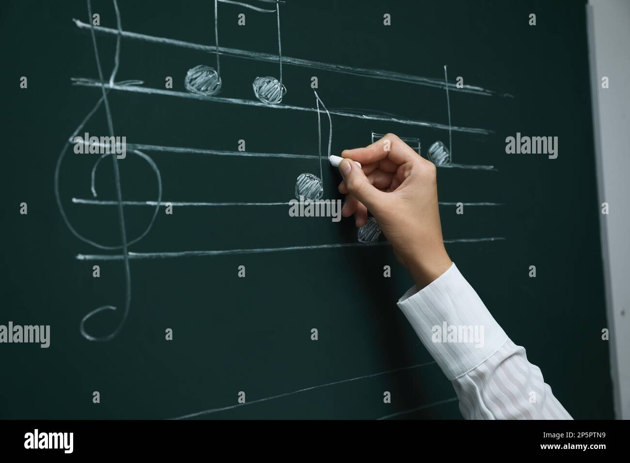 Teacher writing music notes with chalk on greenboard, closeup Stock ...