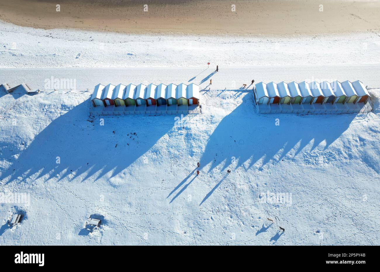 People walk their dogs through the snow beside the beach huts at Blyth ...