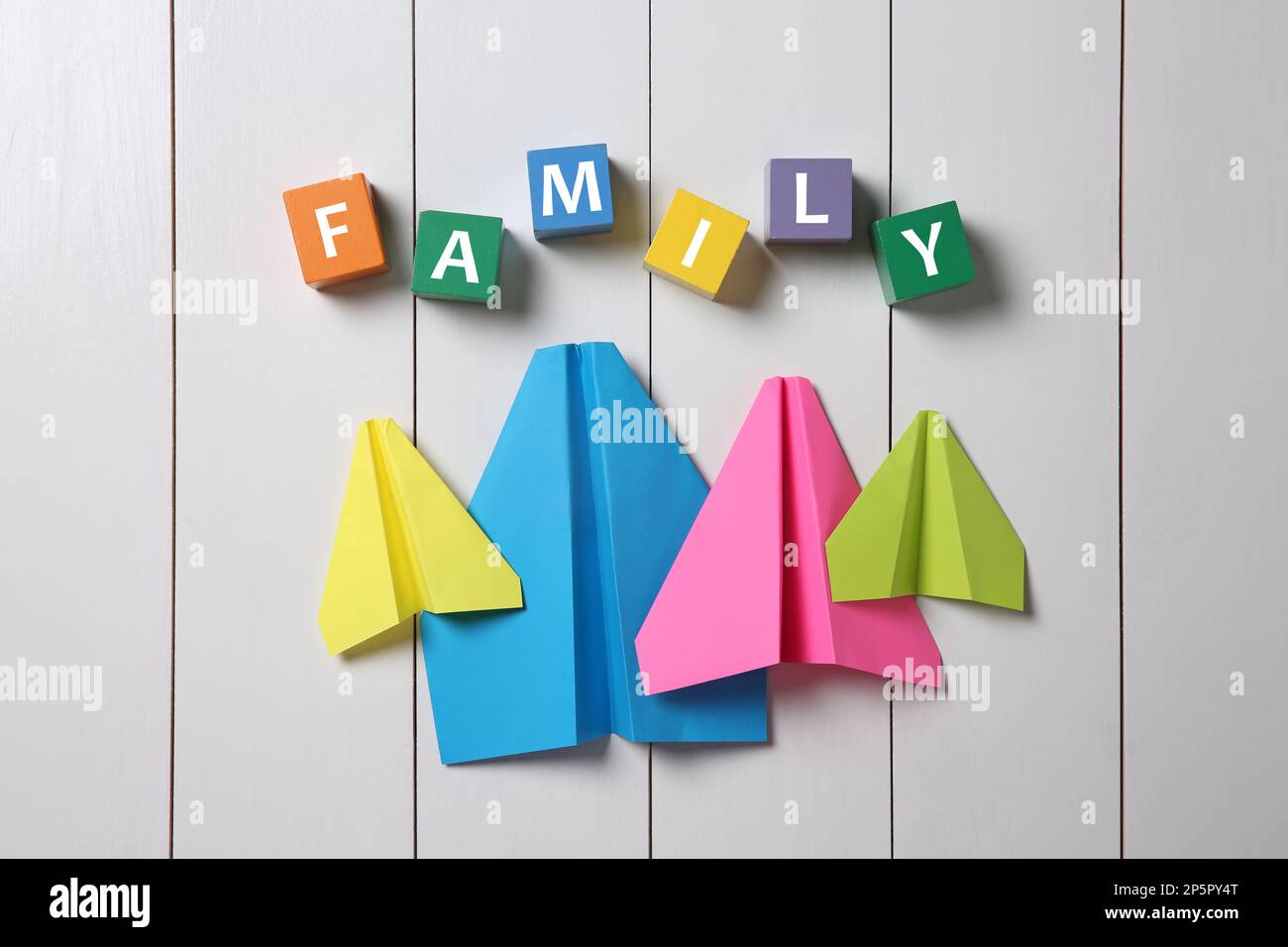 Paper planes and colorful cubes with word Family on white wooden ...