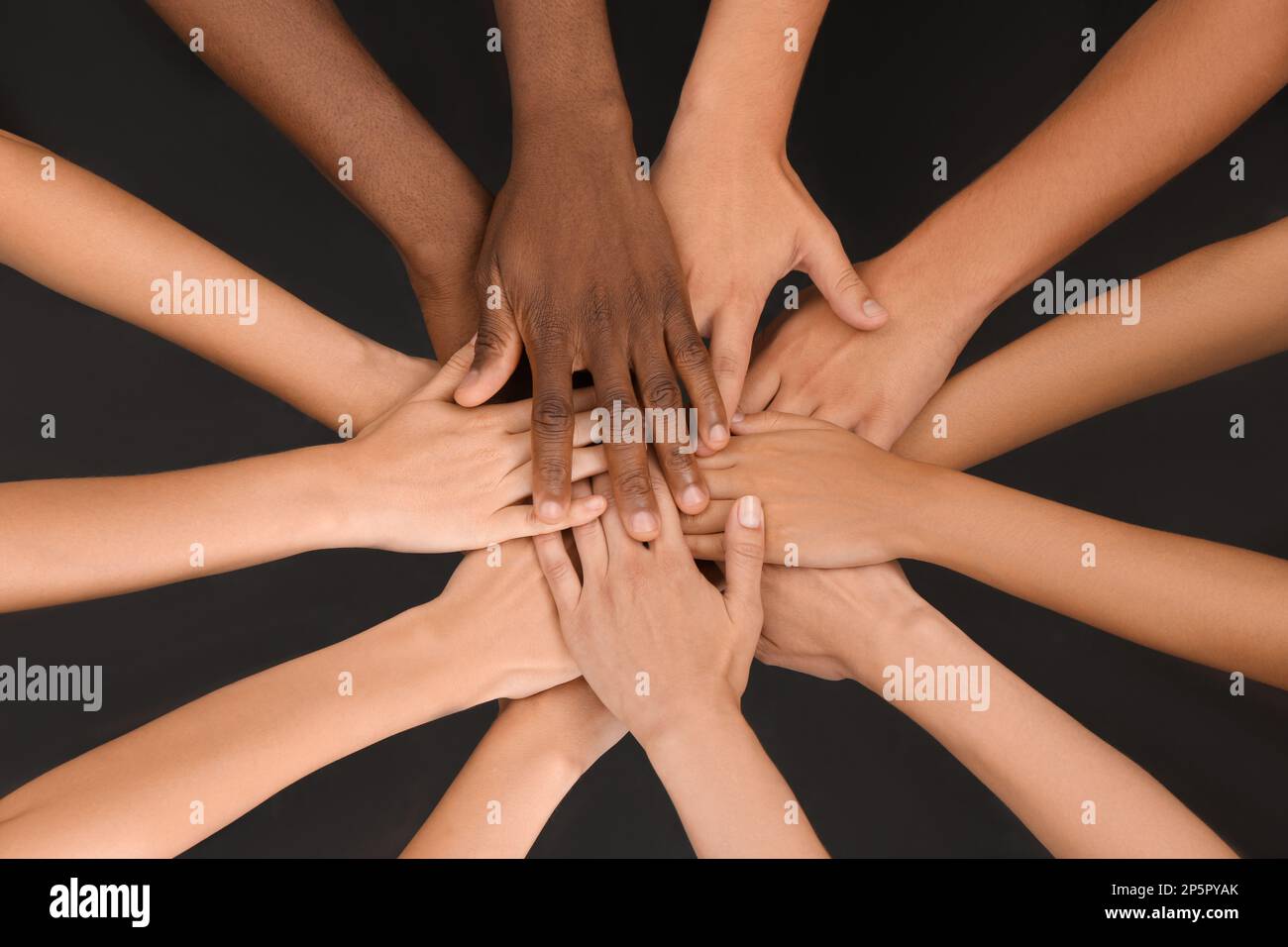 Group of multiracial people joining hands together on black background ...