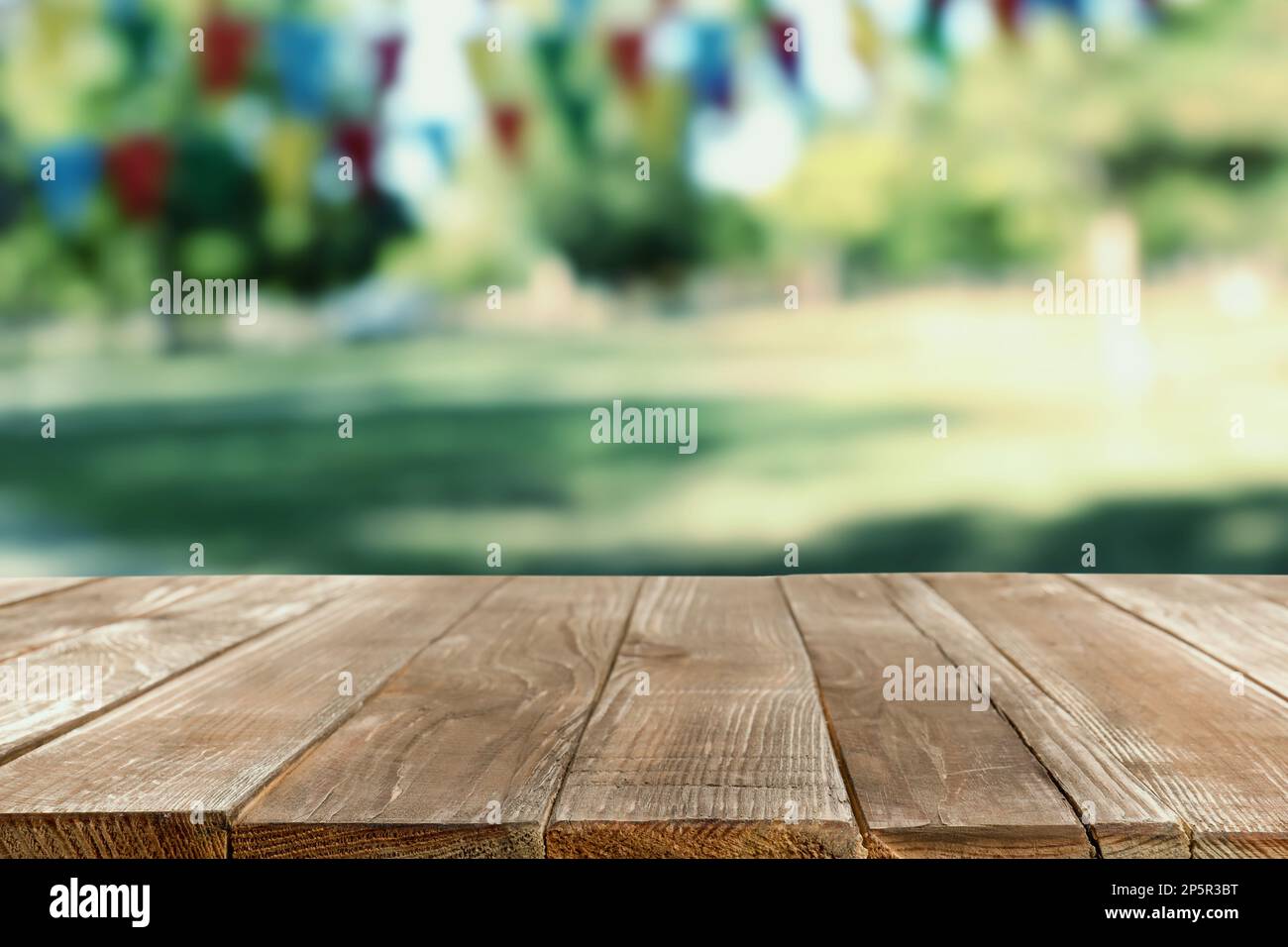 Empty wooden table in park decorated with bunting flags, space for ...