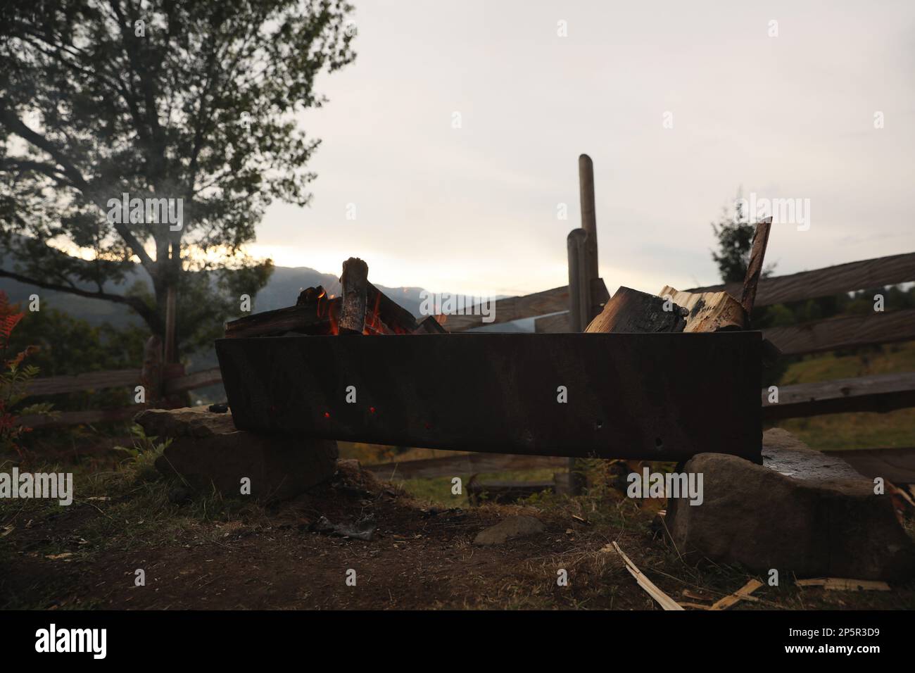 Old metal barbecue with burning firewood outdoors Stock Photo - Alamy