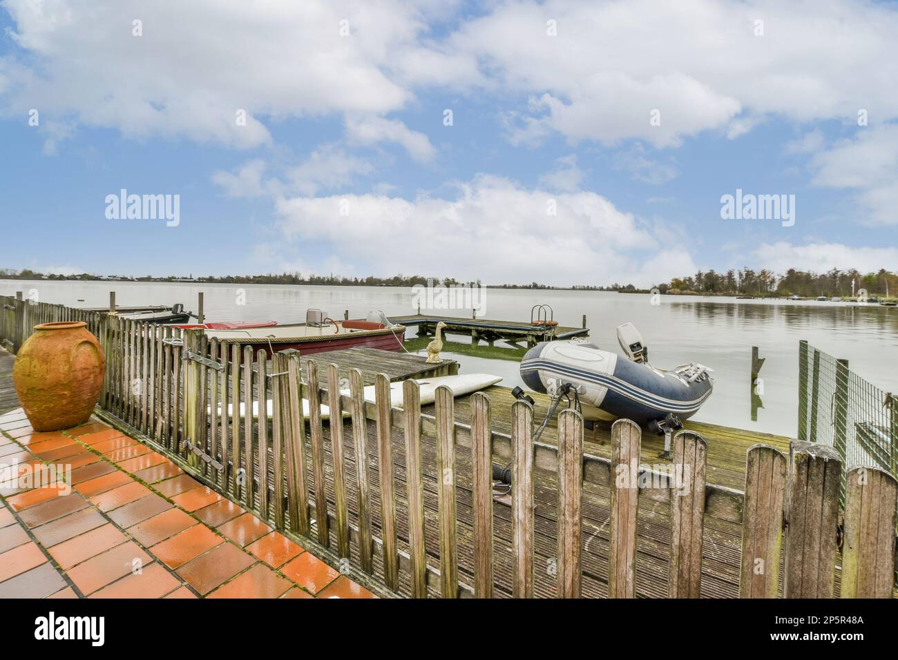 a boat docked on the dock in front of a body of water with clouds and ...