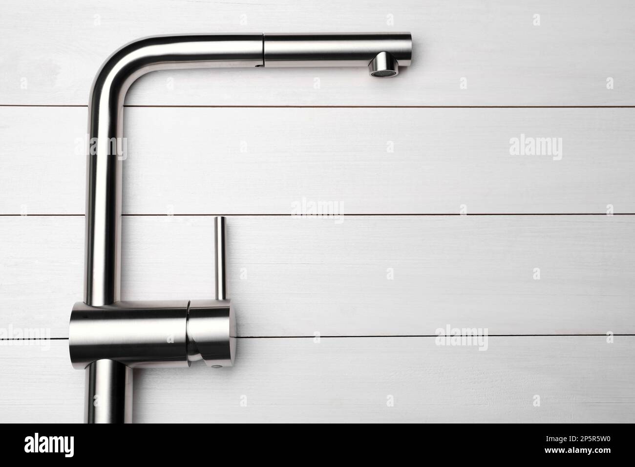 Modern pull out kitchen tap on white wooden table, top view. Space for ...