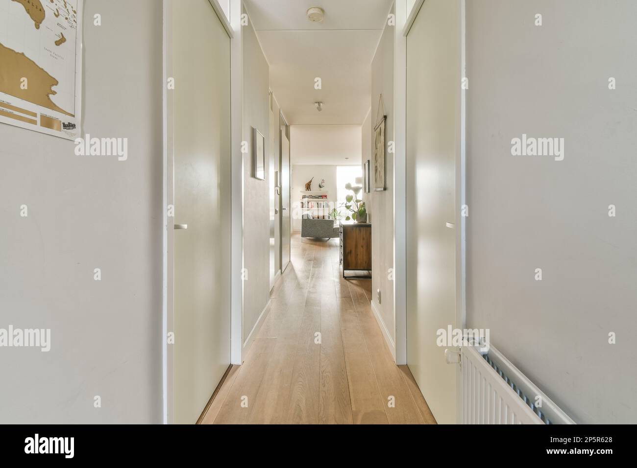 a long narrow hallway with white walls and wood flooring on either side ...