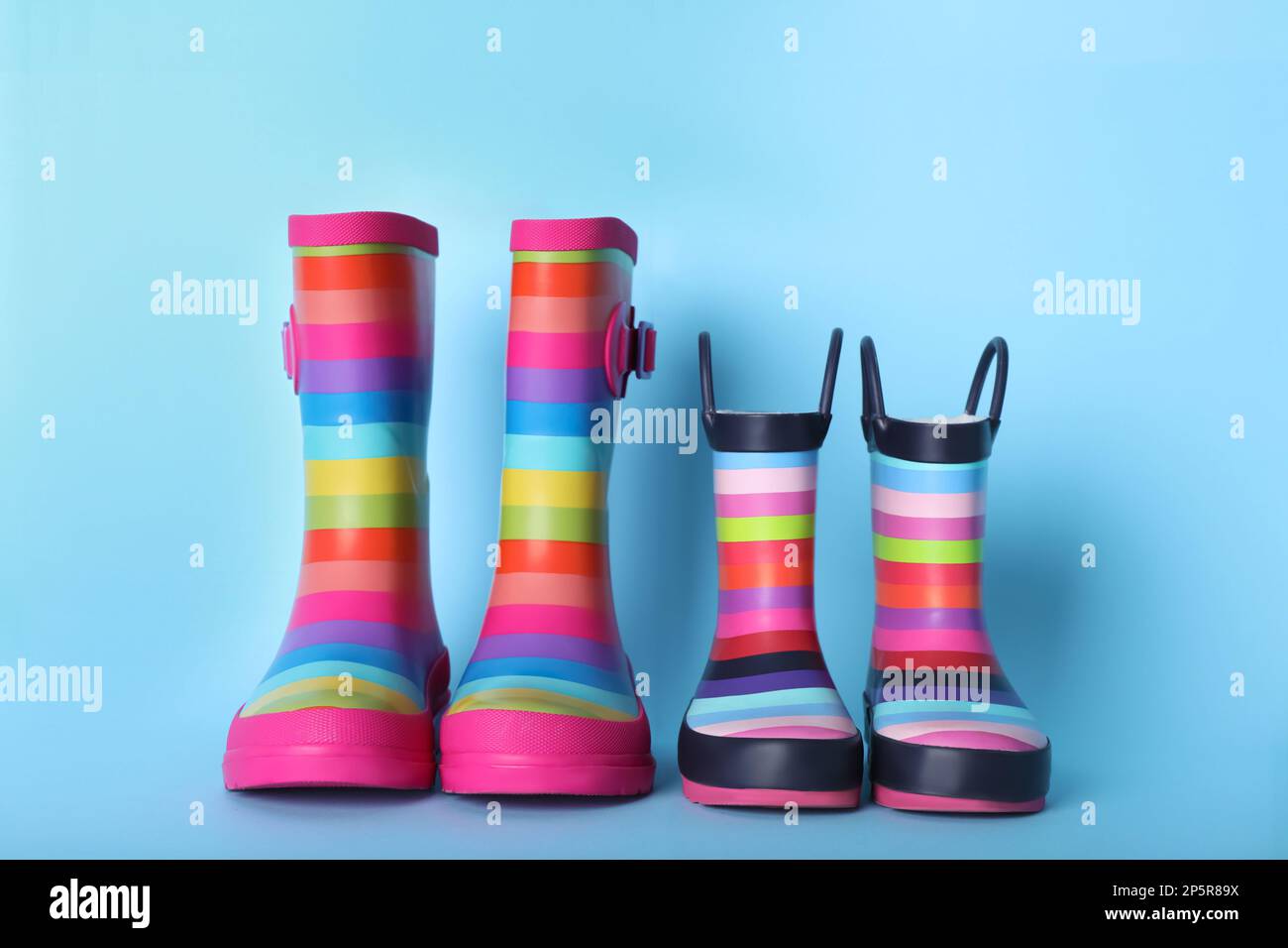Two pairs of striped rubber boots on light blue background Stock Photo ...