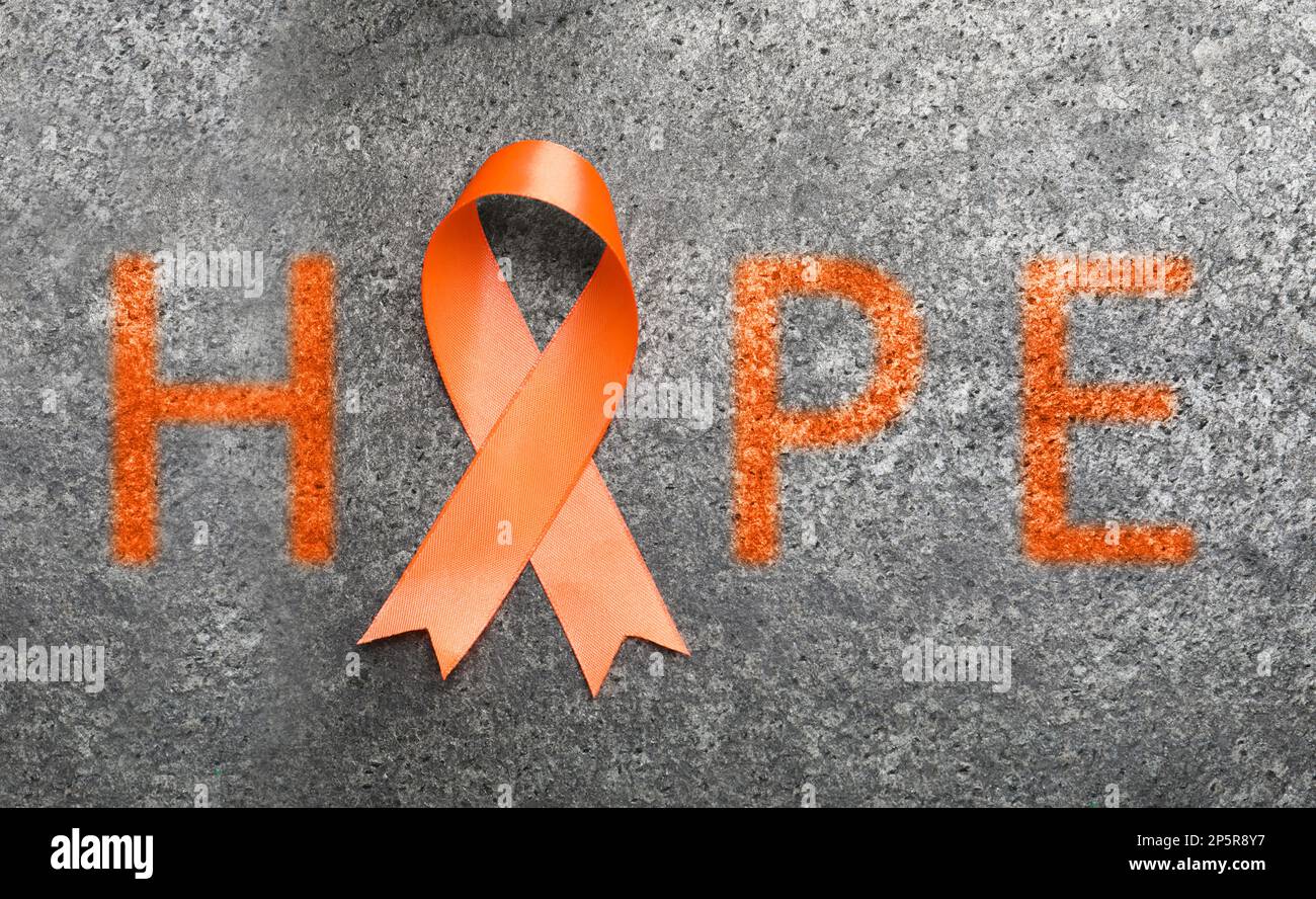 Orange awareness ribbon and word HOPE on grey background, top view ...