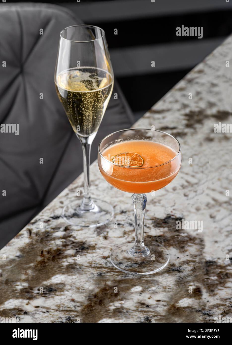 Champagne coupe glass of refreshing orange cocktail on gray table ...