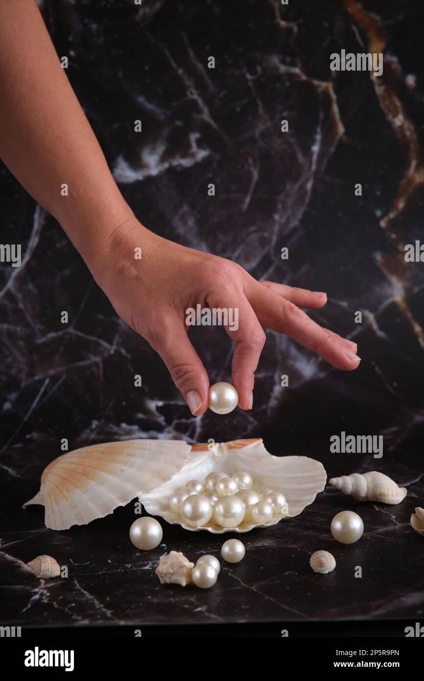pearls on the table in a shell and one in your hand Stock Photo - Alamy
