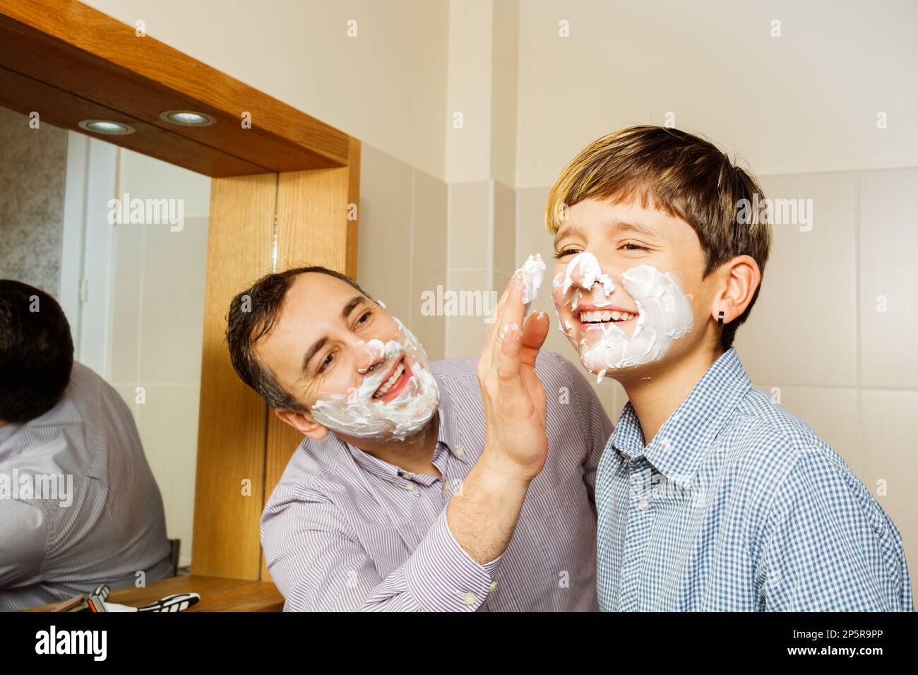 Funny laughing teen with father foaming his face before shave Stock ...