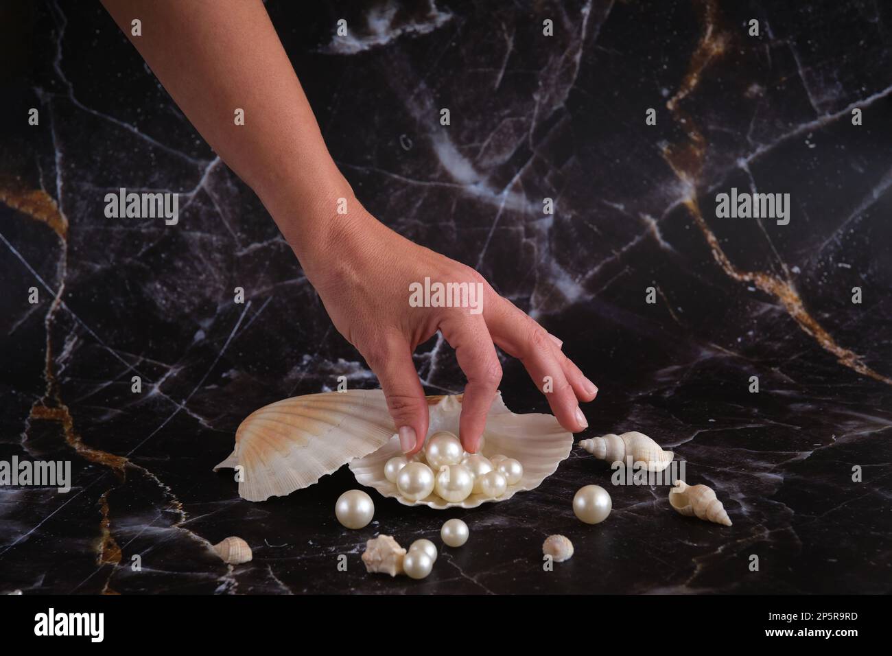 pearls on the table in a shell and one in your hand Stock Photo - Alamy