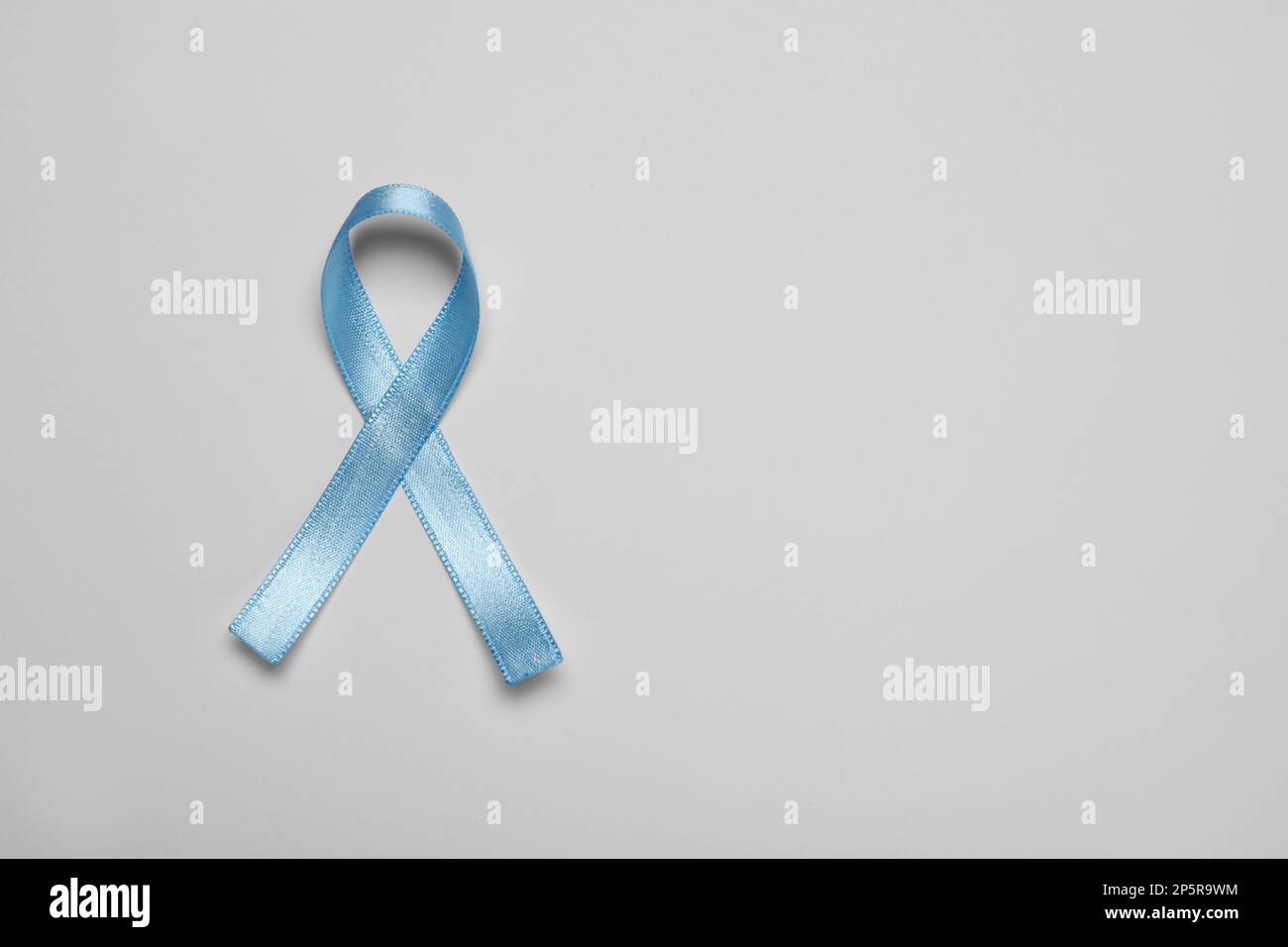 Light blue awareness ribbon on color background, top view. Space for ...