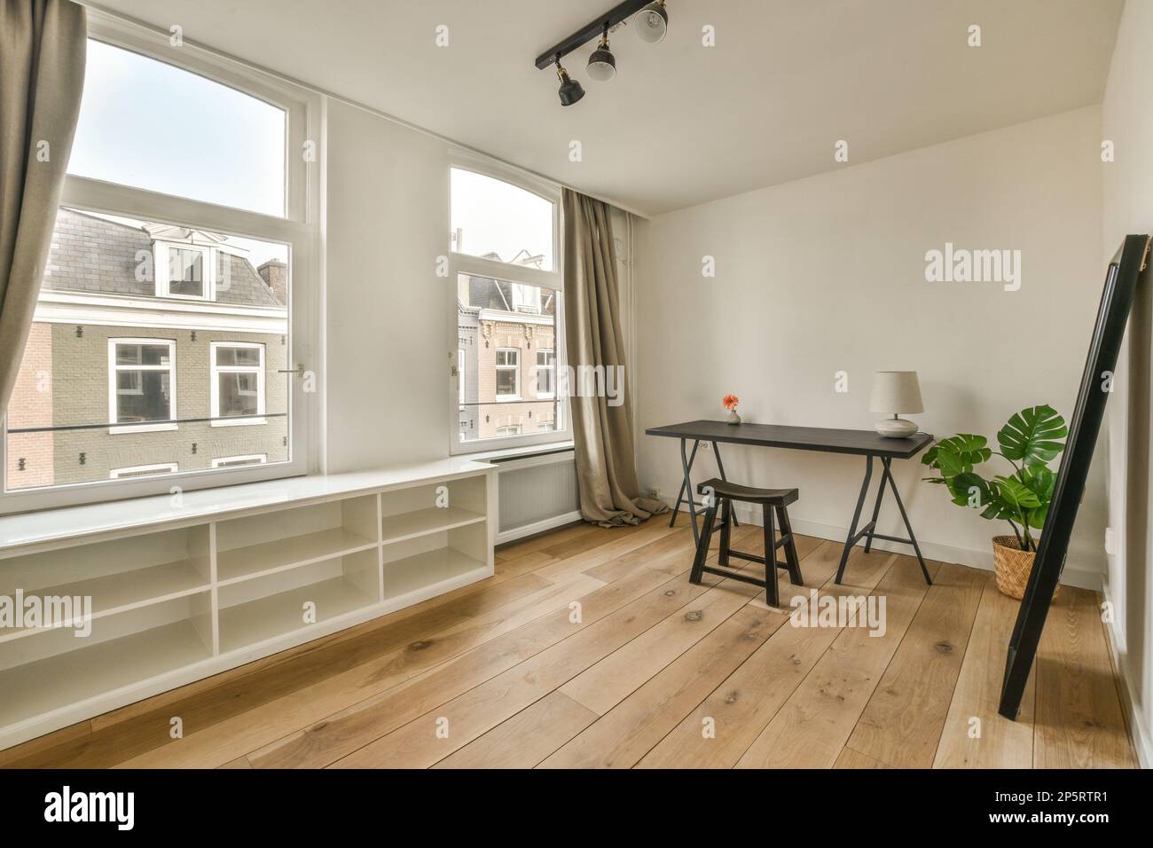 a living room with wood flooring and large windows looking out onto the ...