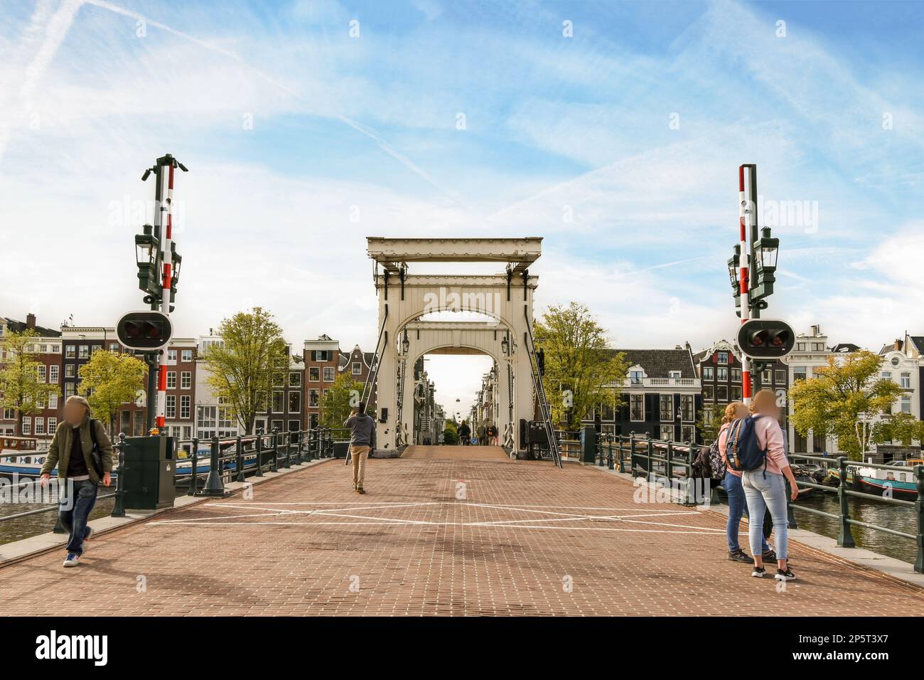 two people walking across a bridge on a bricked walkway in the sky is ...