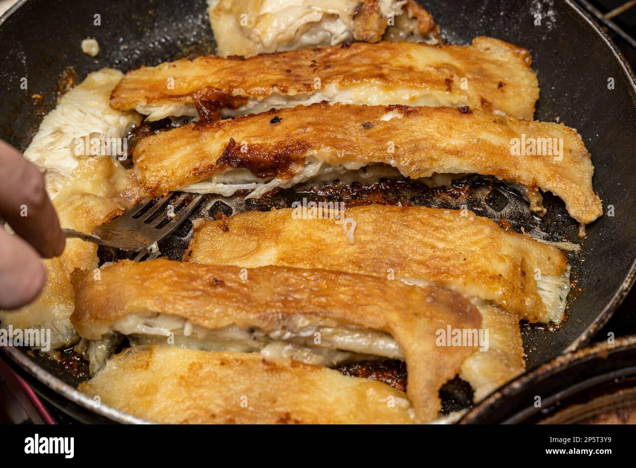 the cook checks the readiness of the fish with a fork Stock Photo - Alamy