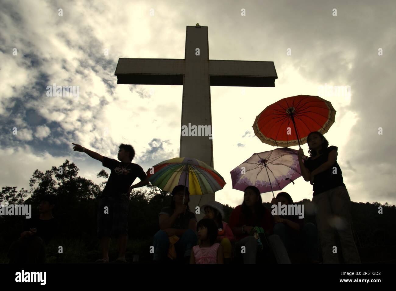 Silhouette of visitors and a tall Christian cross at Bukit Kasih (Hill ...