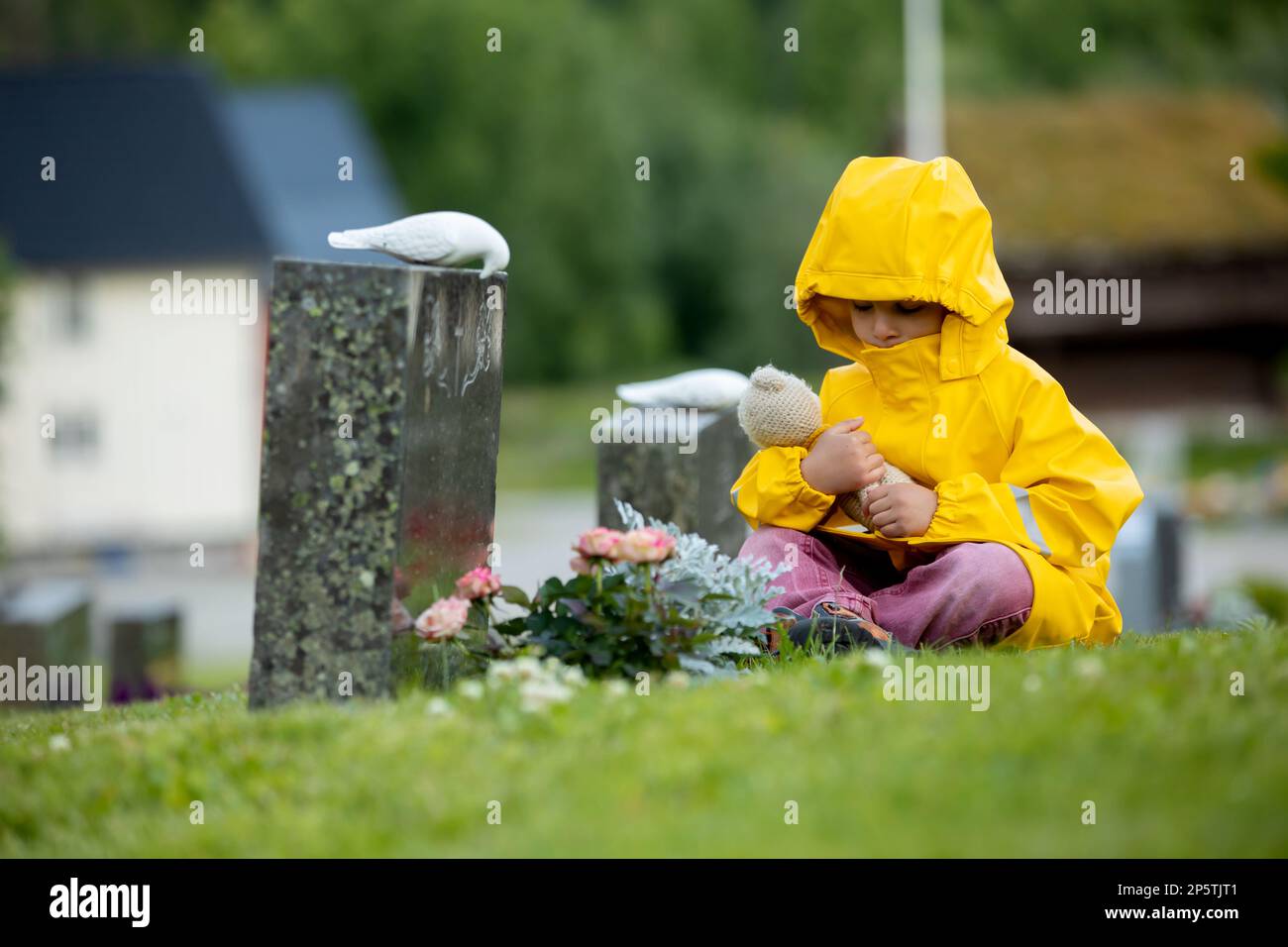 Sad little child, blond boy, standing in the rain on cemetery, sad ...