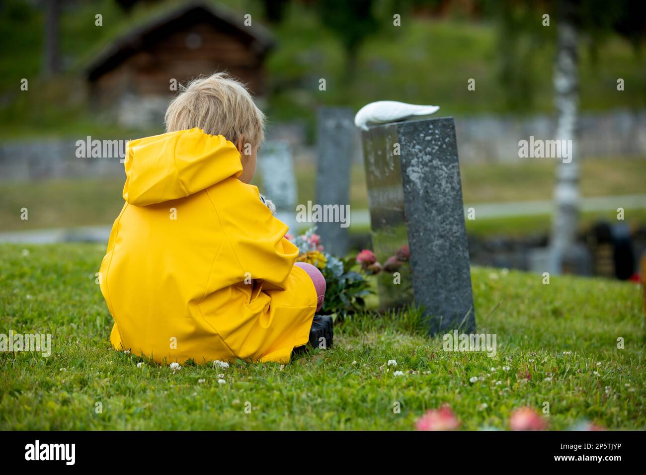 Sad little child, blond boy, standing in the rain on cemetery, sad ...