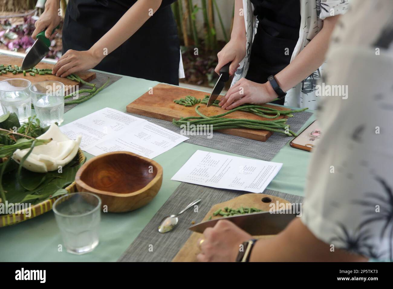 Adult students learning recipe and preparing meal in cooking class ...