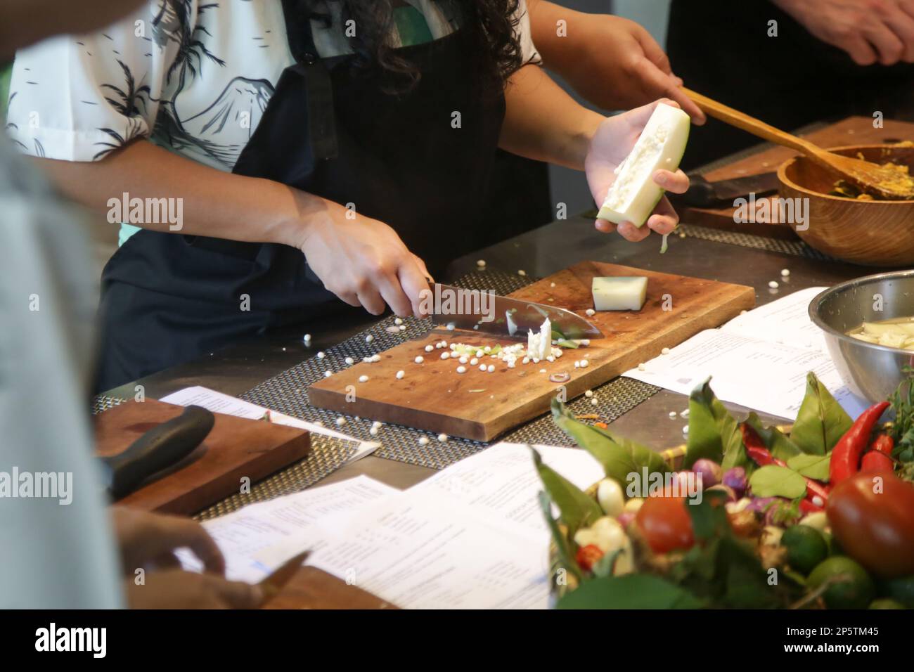 Adult students learning recipe and preparing meal in cooking class ...
